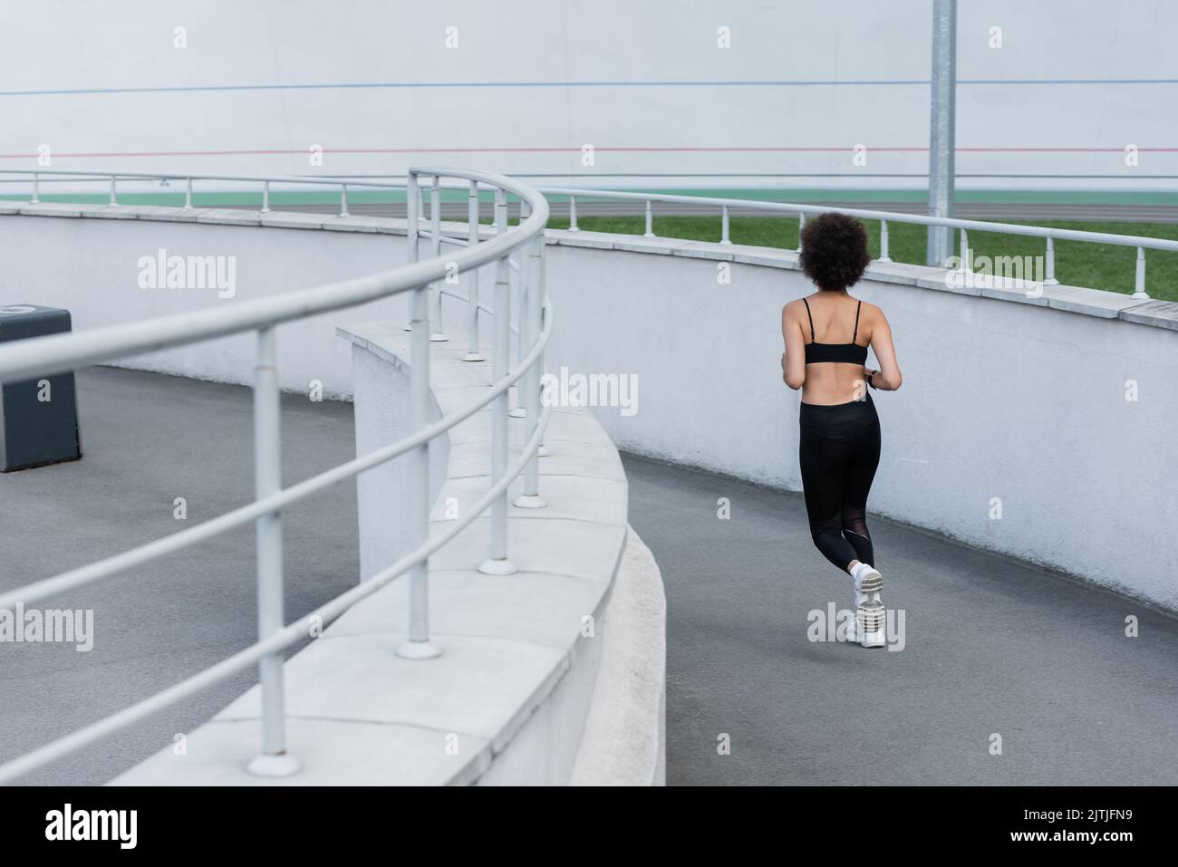 back view of brunette african american sportswoman running on stadium ...