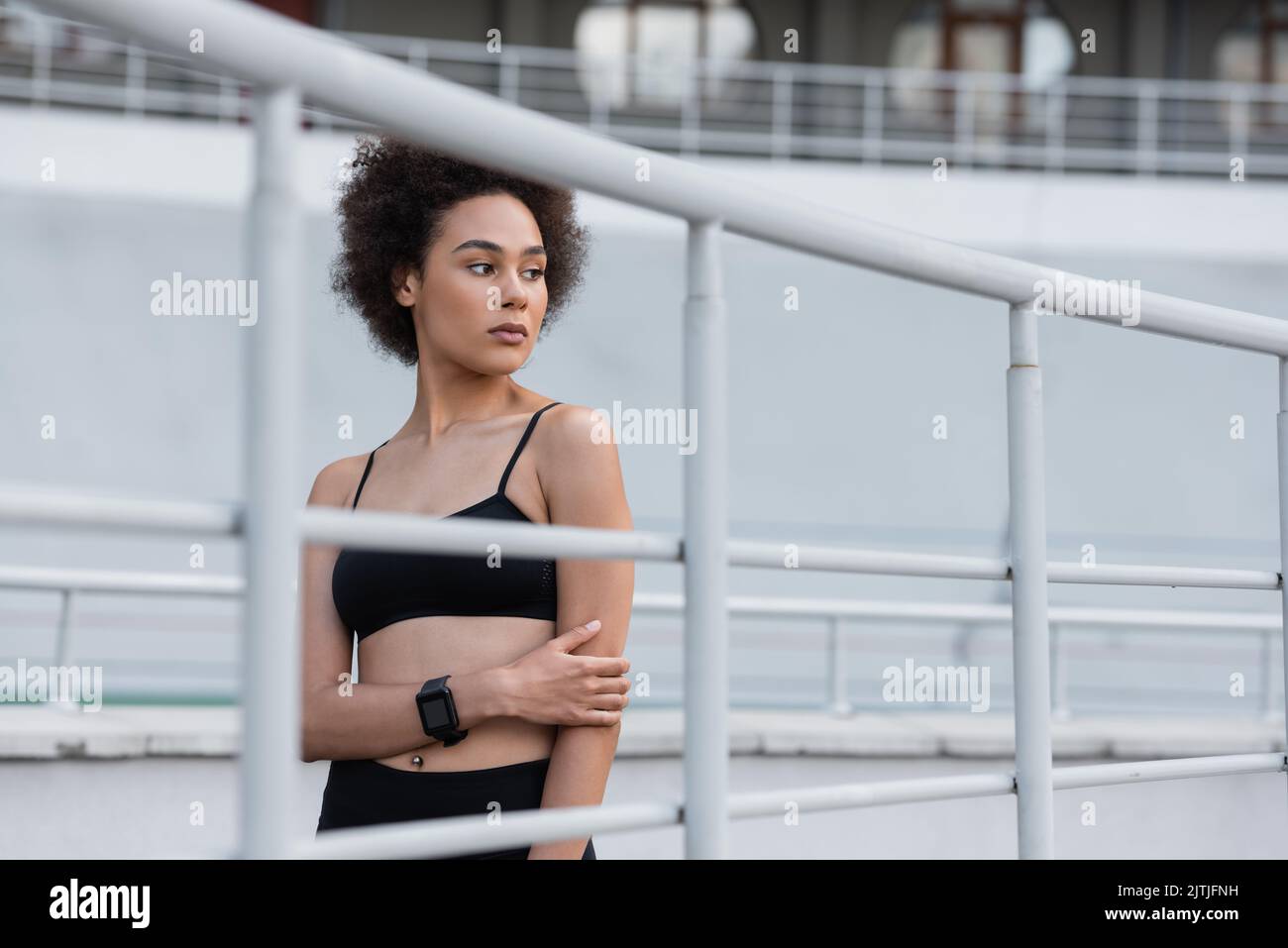 curly african american woman in black sports bra and fitness tracker ...