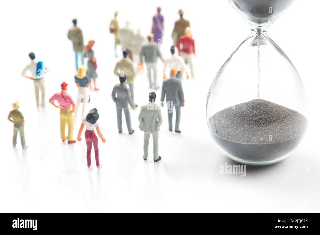 miniature people. different people are walking next to the hourglass on ...