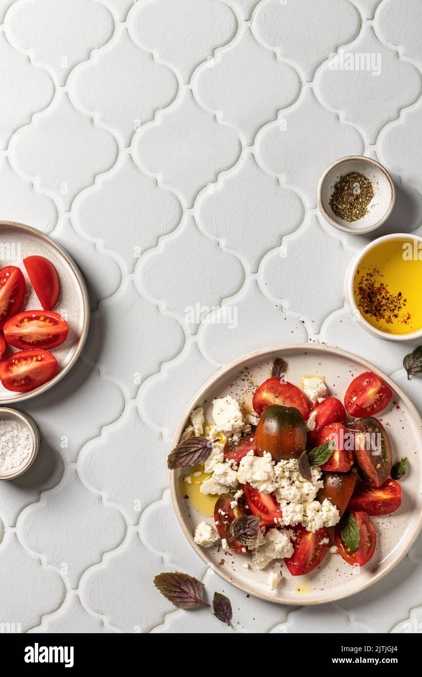 Tomato salad with feta cheese and bazil leaves served with cutlery on ...