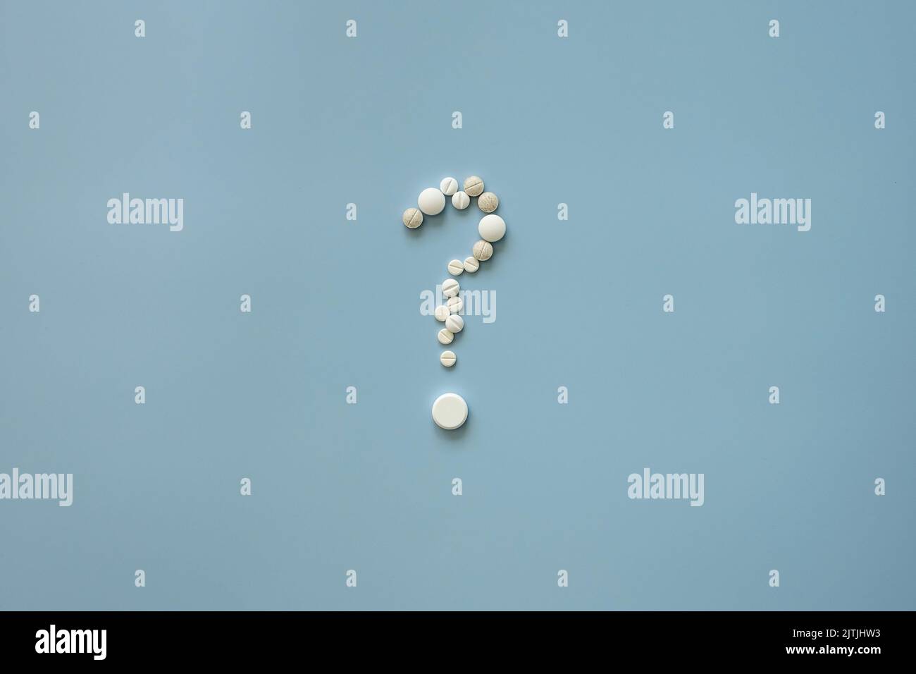 Pills are laid out in the form of a question mark, on a blue background ...