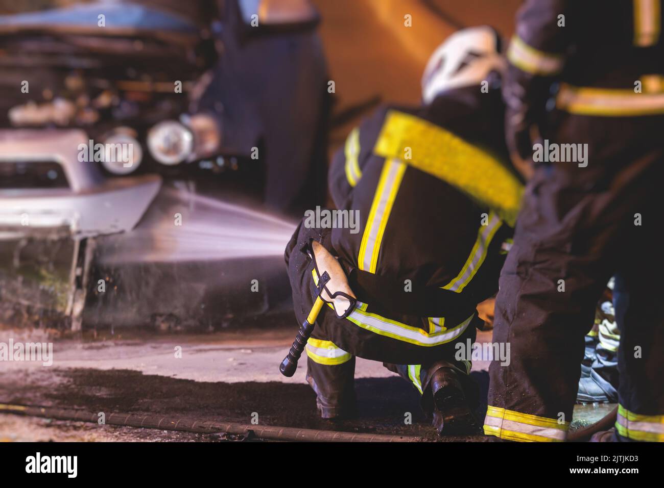 Group of fire men extinguishing and put out burning car crash after ...