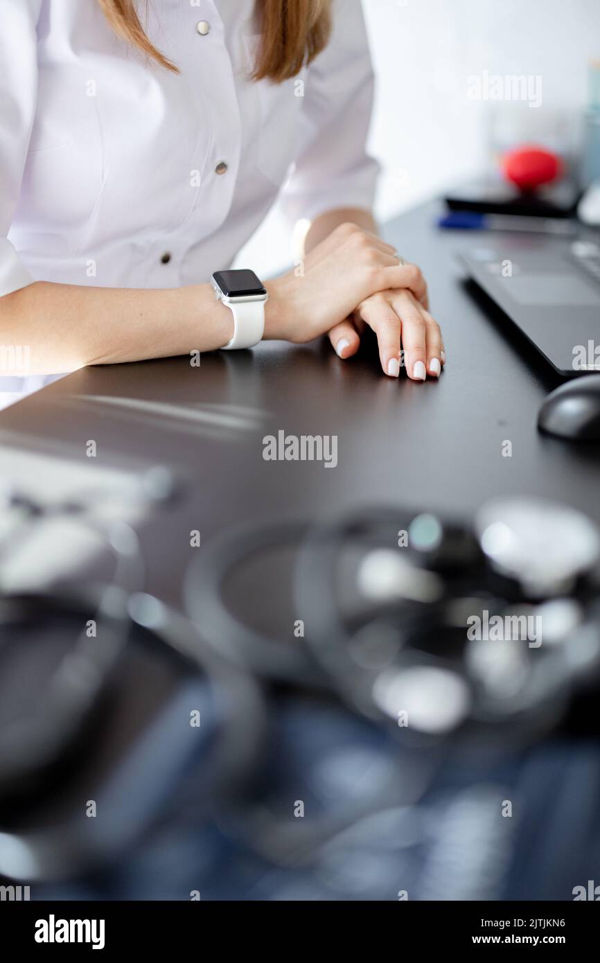Woman doctor sits at desk in clinic against background of medical ...