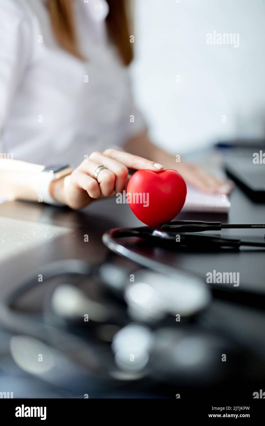 Woman cardiologist doctor shows heart red model in clinic. Concept of ...