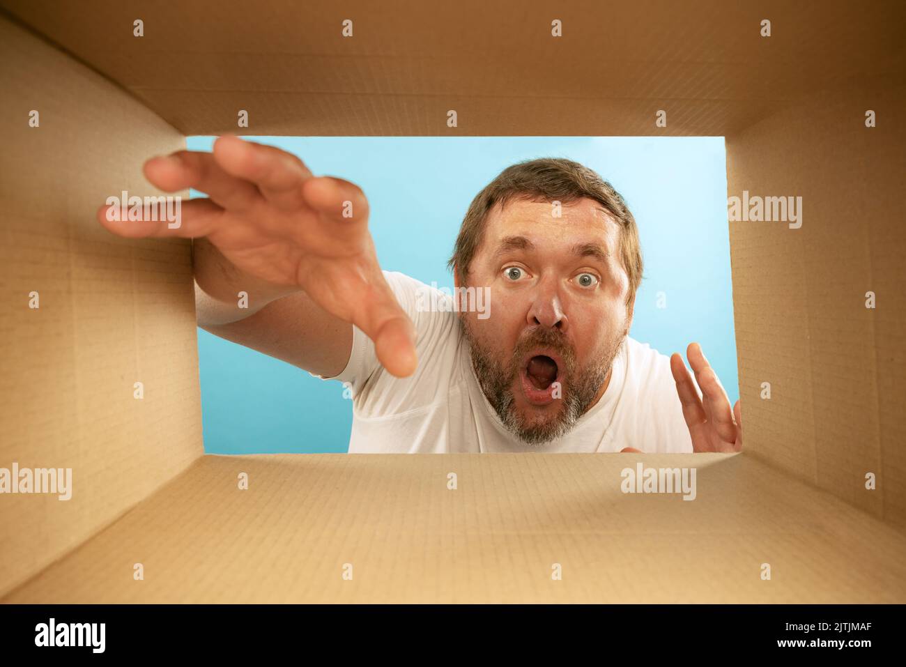 Shocked man unpacking opening carton box and looking inside. Delivery ...