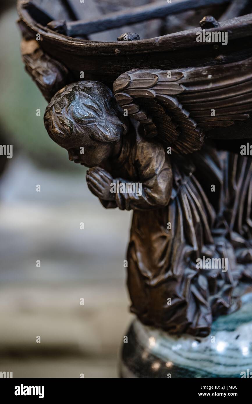 A vertical shot of a praying child angel sculpture in a Scottish castle ...