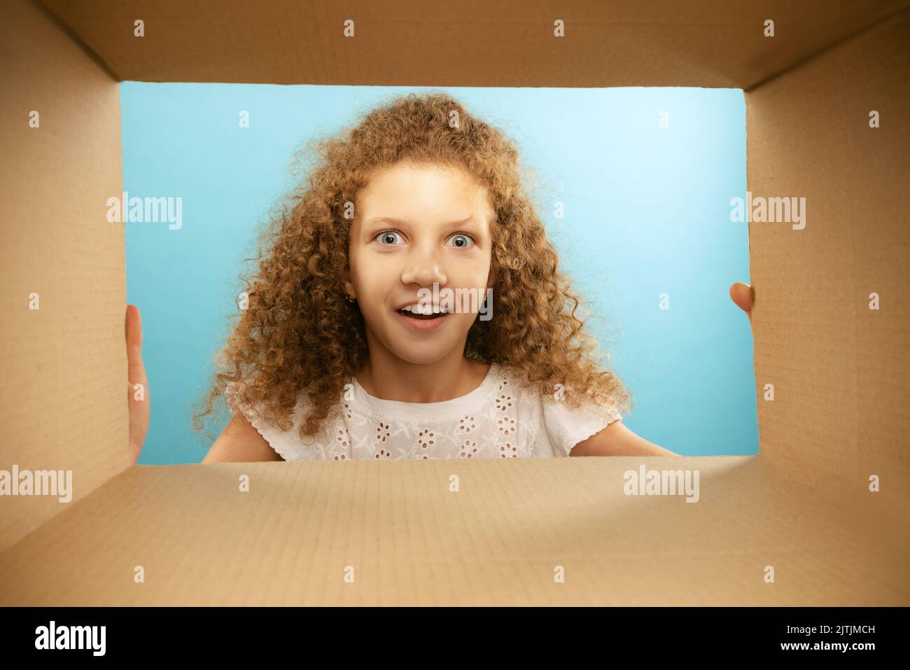 Happy smiling kid, little girl looking inside box during opening ...