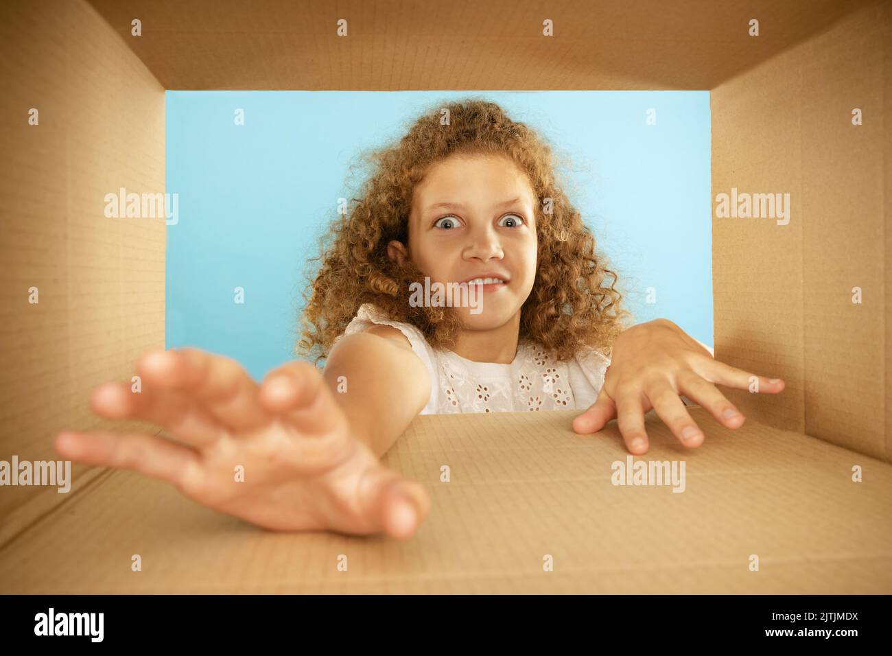 Take it. Happy smiling kid, little girl looking inside box during ...