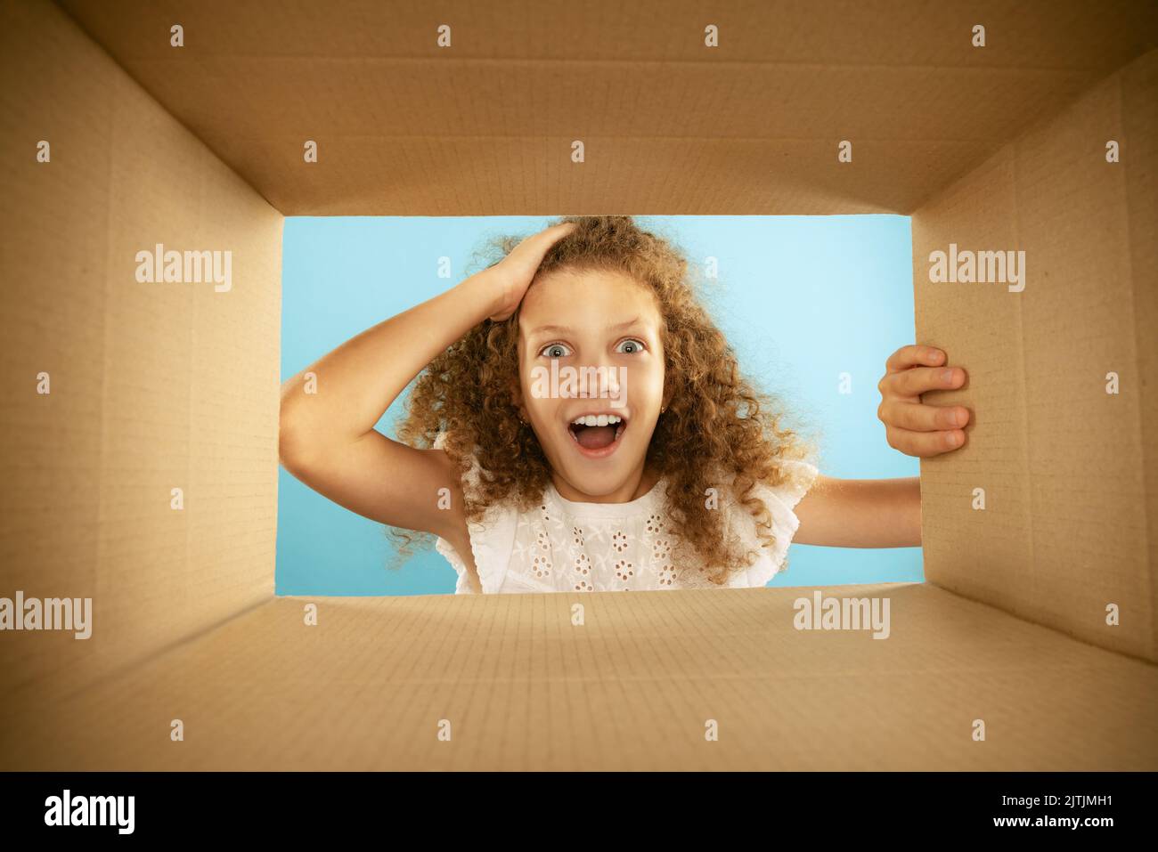 Emotional kid, little girl looking inside box during opening, unpacking ...