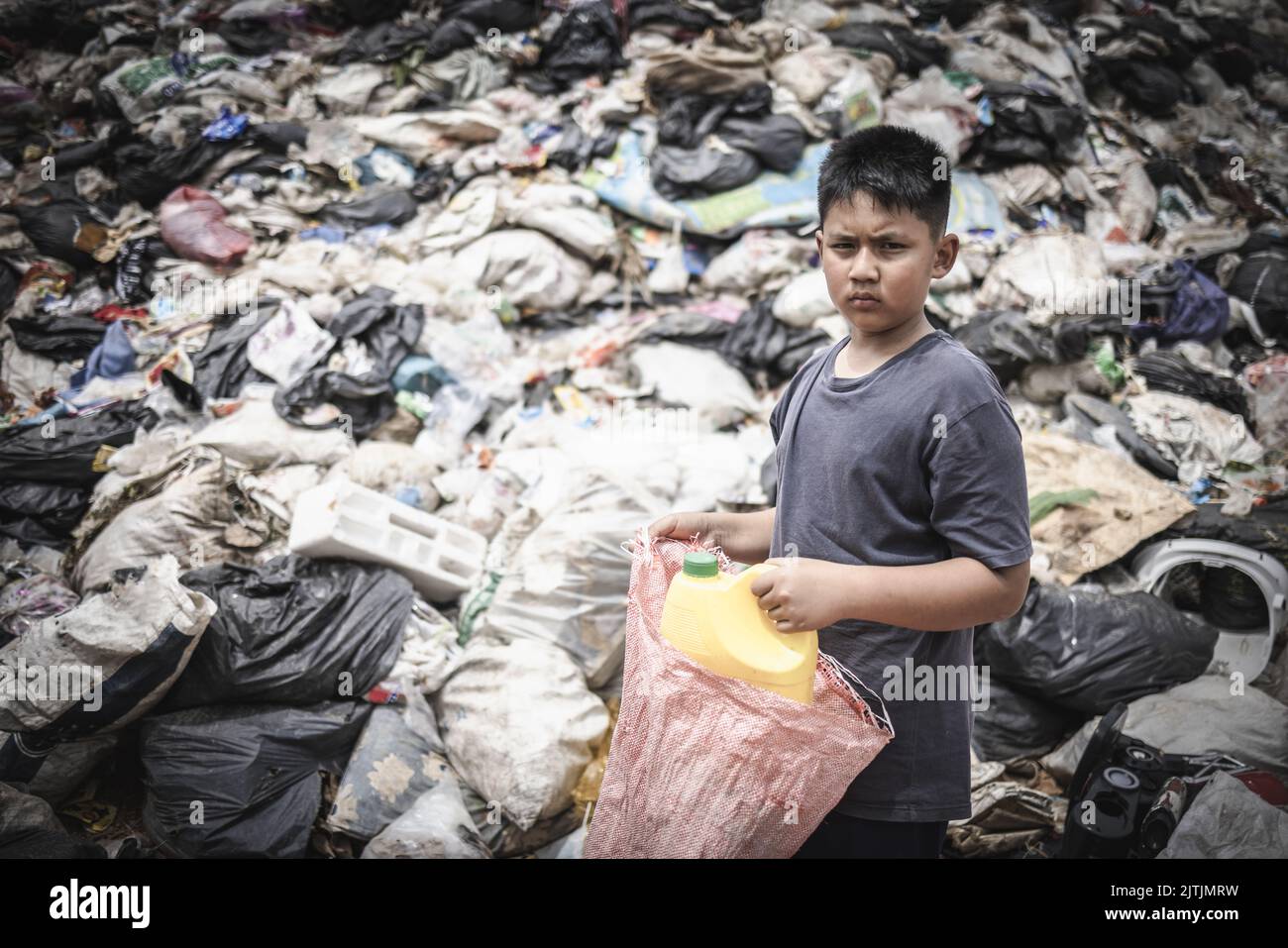 A young poor Indian boy collection waste plastic bottles in his sack to ...