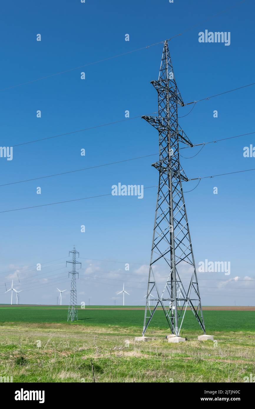 Landscape with electric pole and wind turbine on green agricultural ...