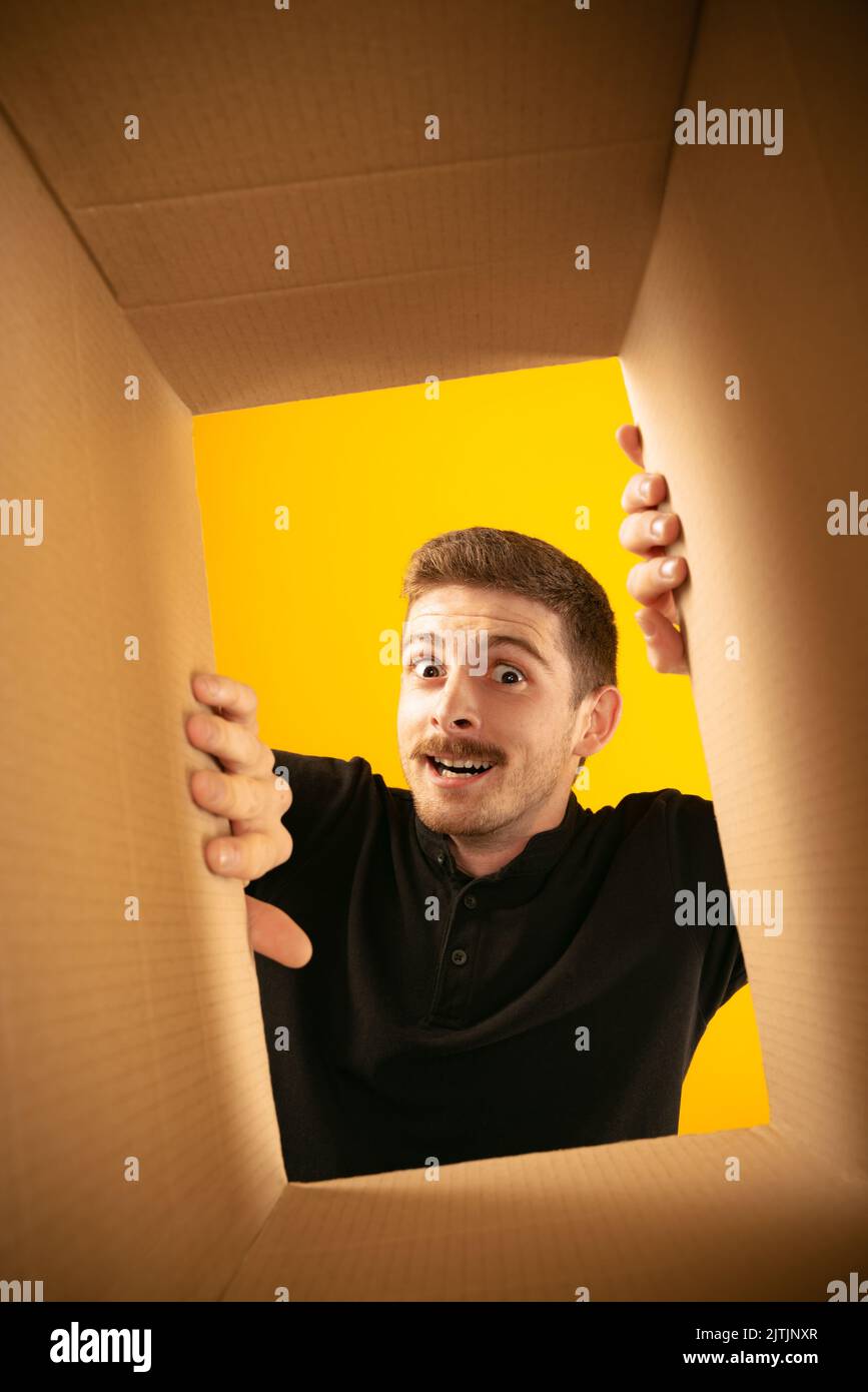 Surprising man unpacking opening carton box and looking inside ...