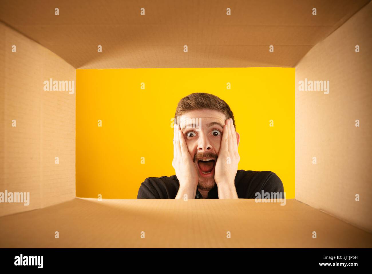 Incredible. Surprised man unpacking, opening carton box and looking ...