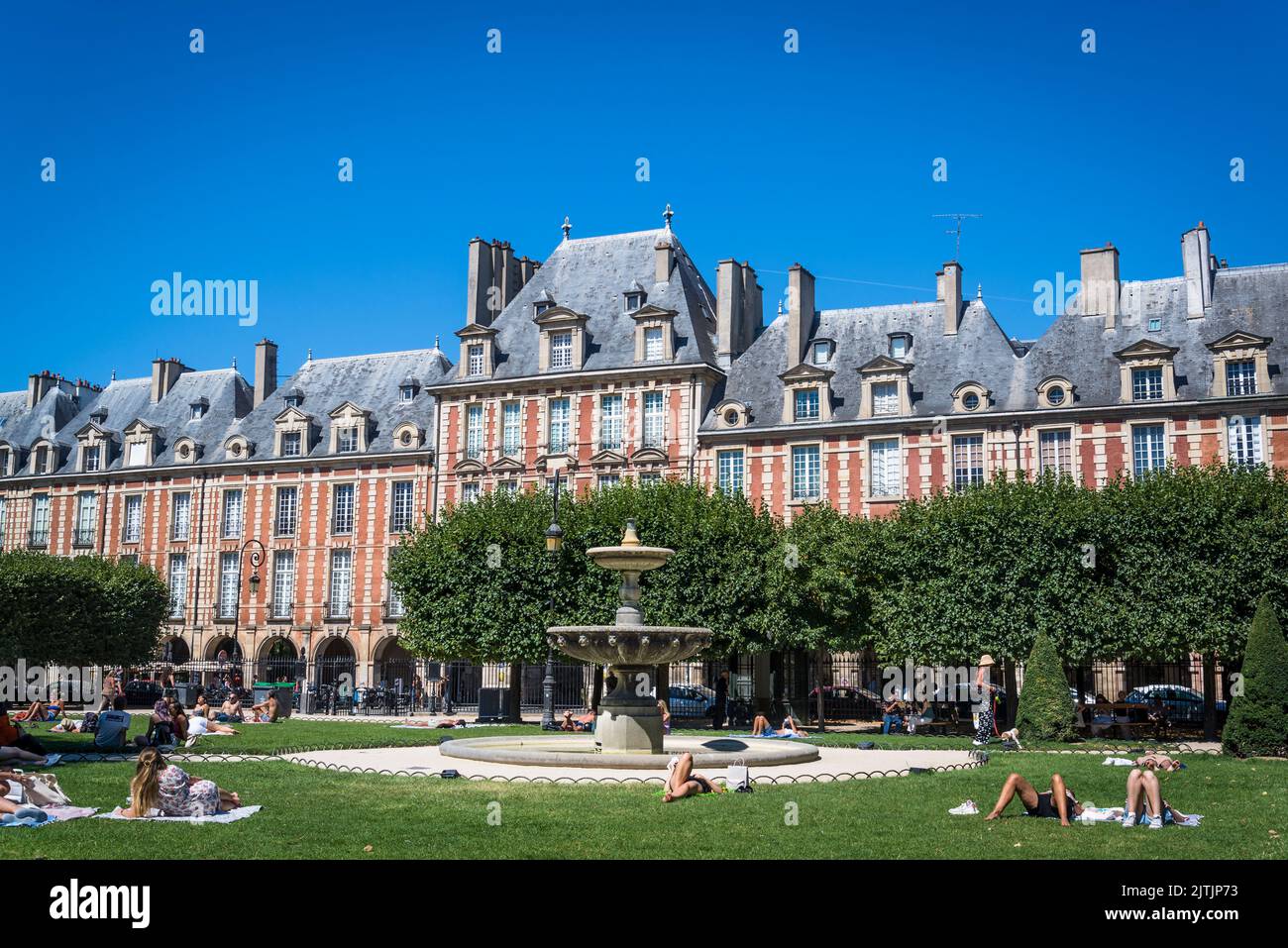 People relaxing in the central park of the Place des Vosges, the oldest ...