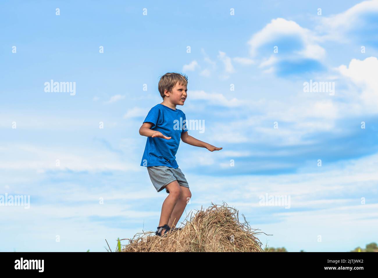 Boy smile play dance grimace show off blue t-shirt stand on haystack ...