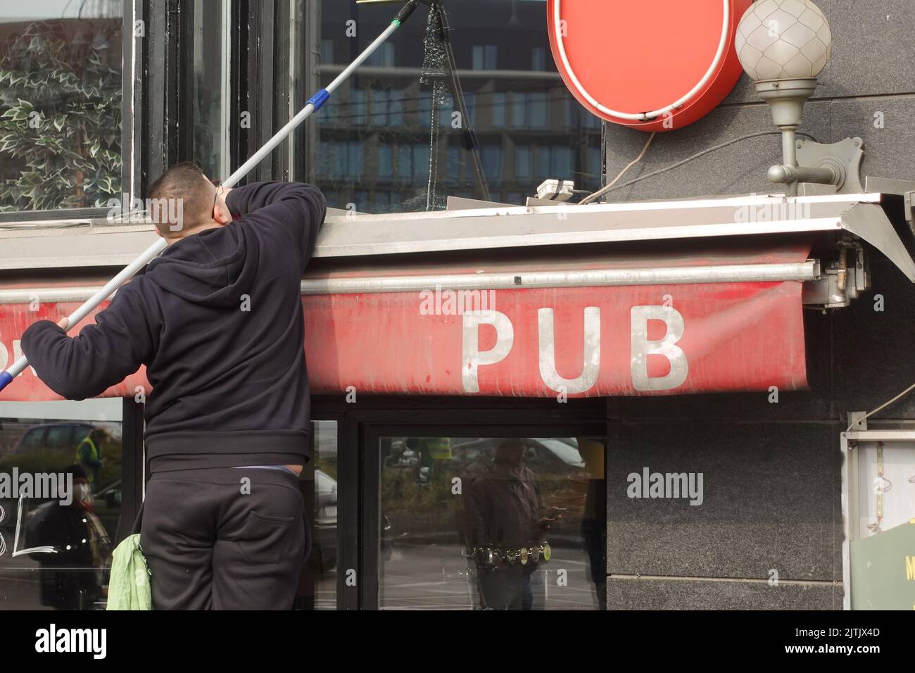 Employee cleaning the shop window of a pub Stock Photo - Alamy
