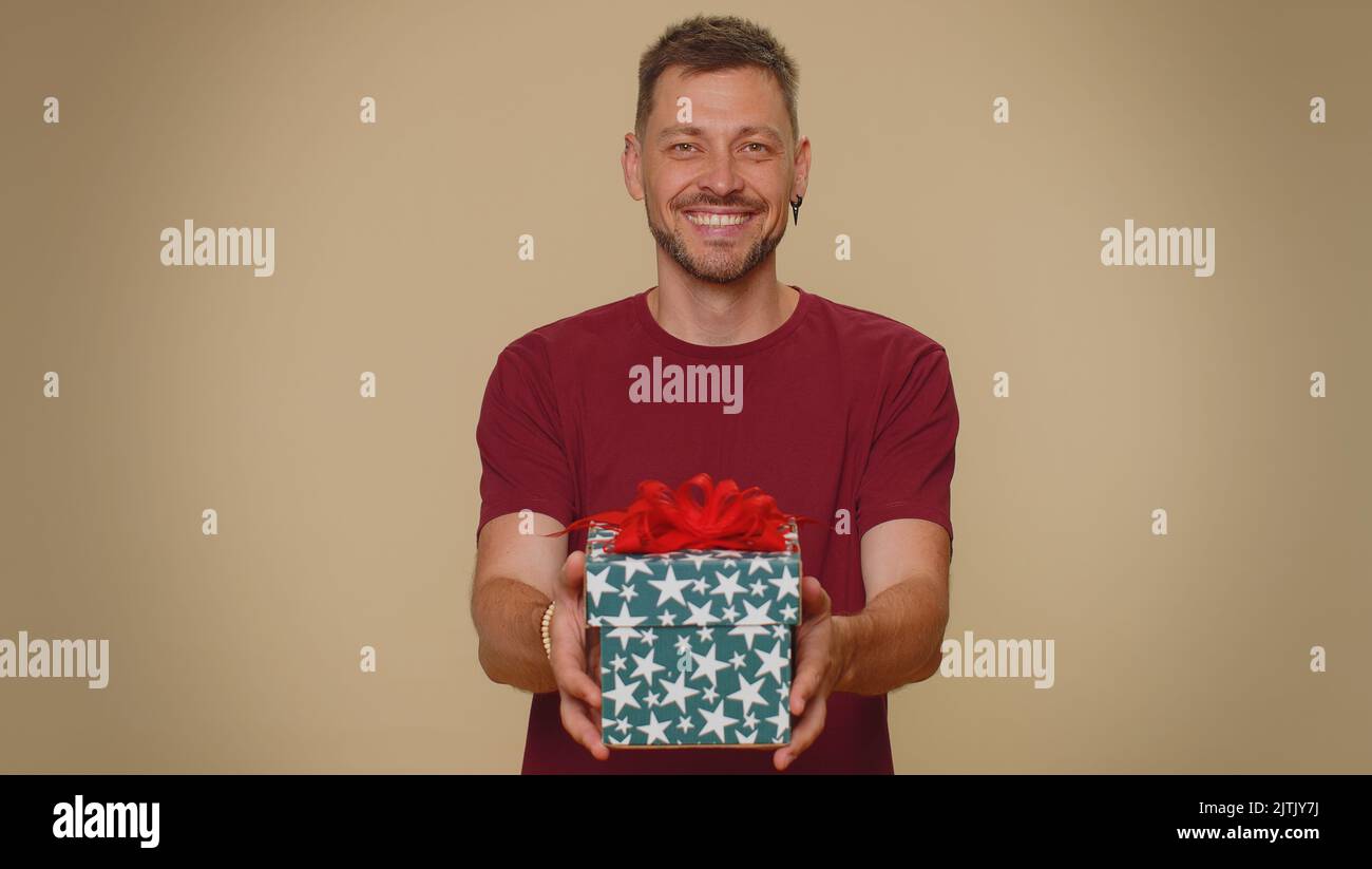 Positive smiling bearded handsome young man presenting birthday gift ...