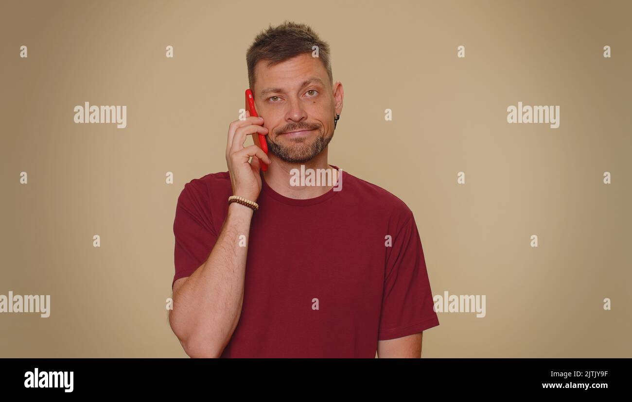 Tired young man in red t-shirt making online conversation speaks on ...