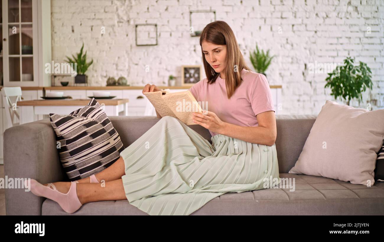 A lady sitting on a sofa and reading her notes from notebook Stock ...