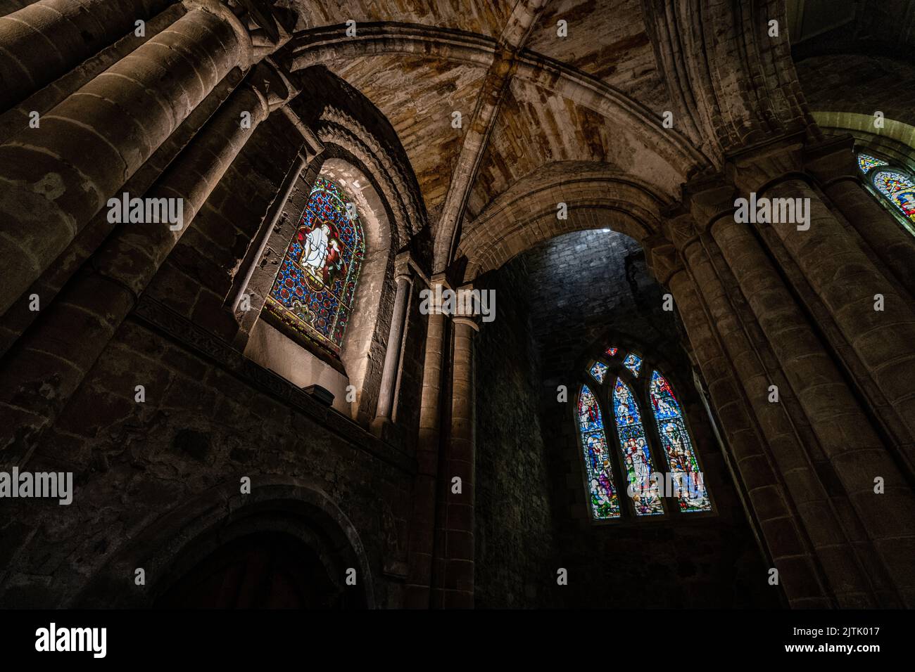 The interior of an ancient stone cathedral with arches and strained ...