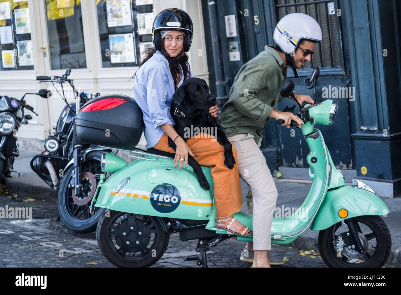 Young couple with their black Labrador dog on a motor-scooter, Paris ...