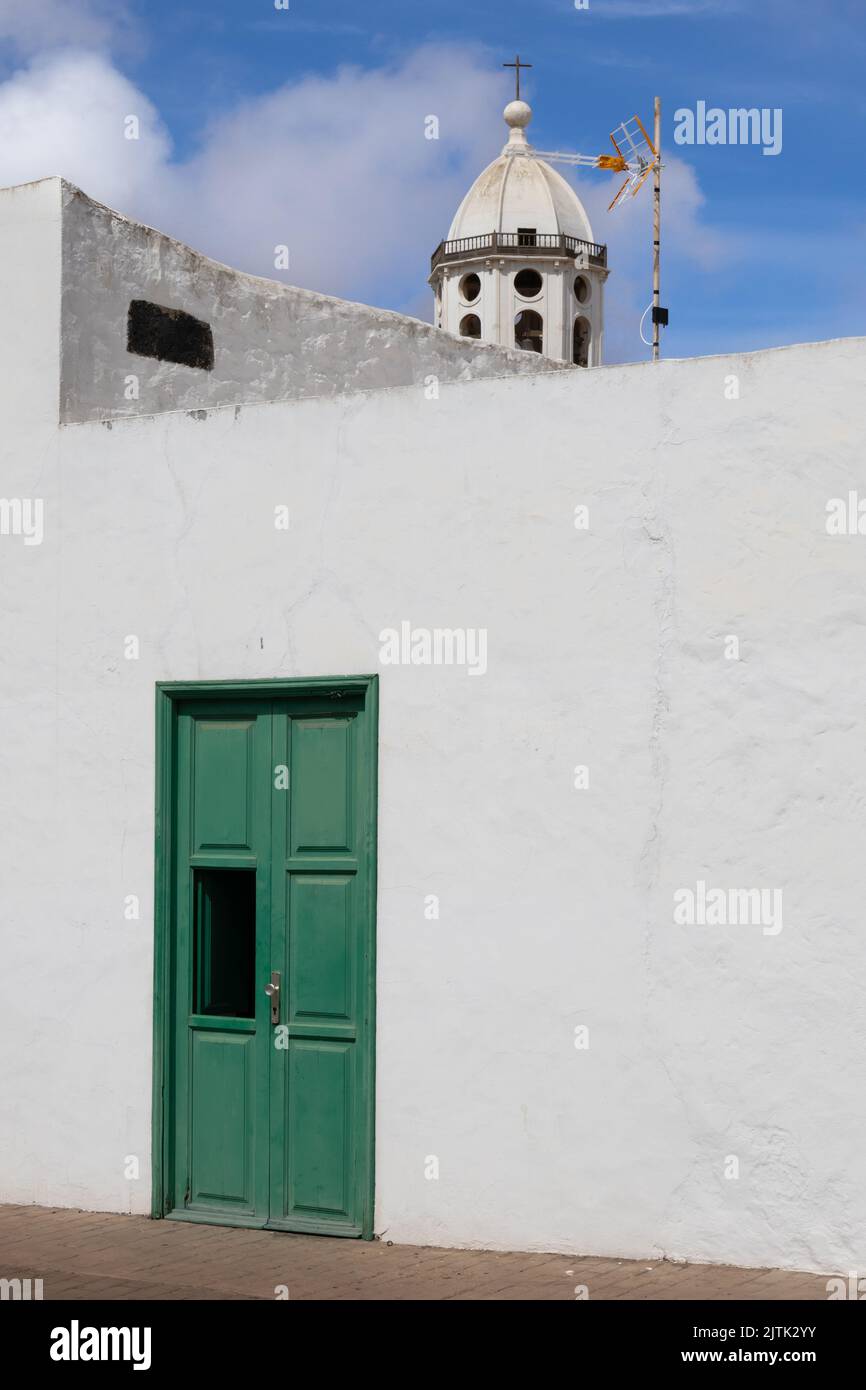 Calm street during siesta. White wall of a buidling with green details ...