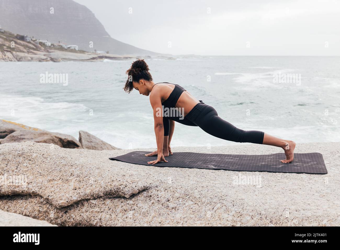 Side view of fit female on mat stretching her body by ocean Stock Photo ...