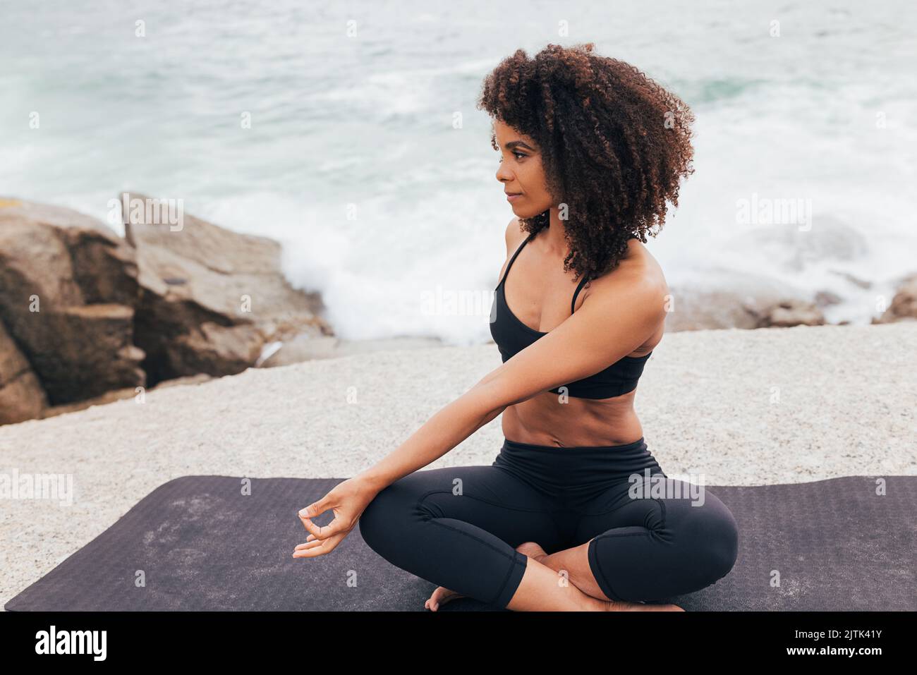 Healthy female with crossed legs flexing her body while practicing yoga ...