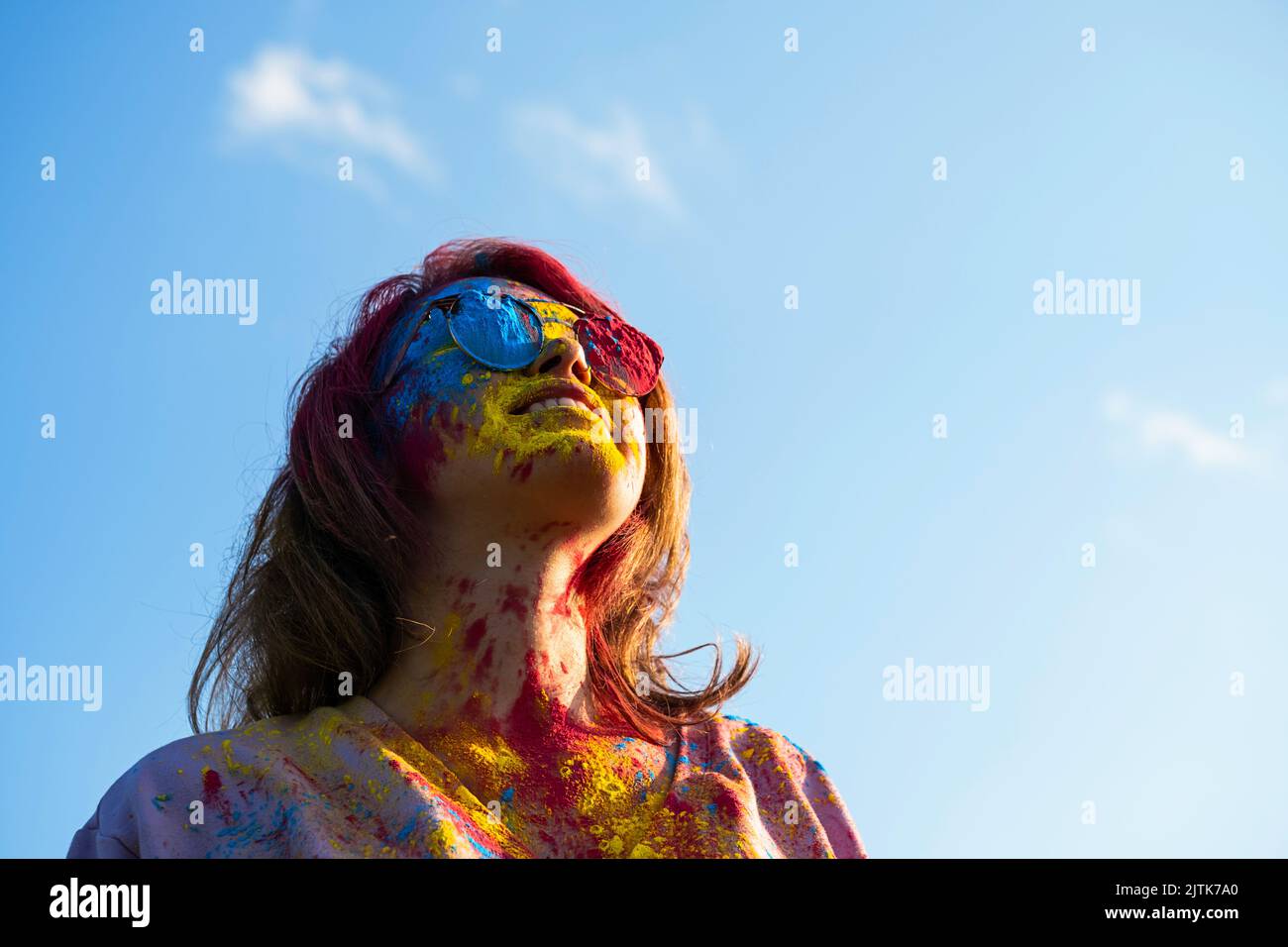 Woman covered in holi powder against blue sky. Holi colours festival ...