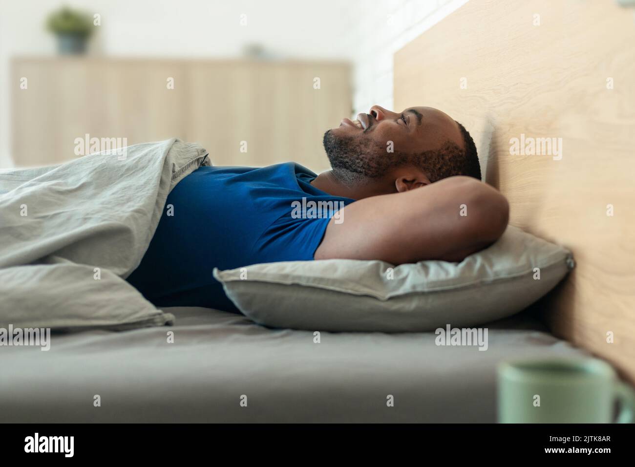 Black Guy Lying In Bed Holding Hands Behind Head Indoor Stock Photo - Alamy