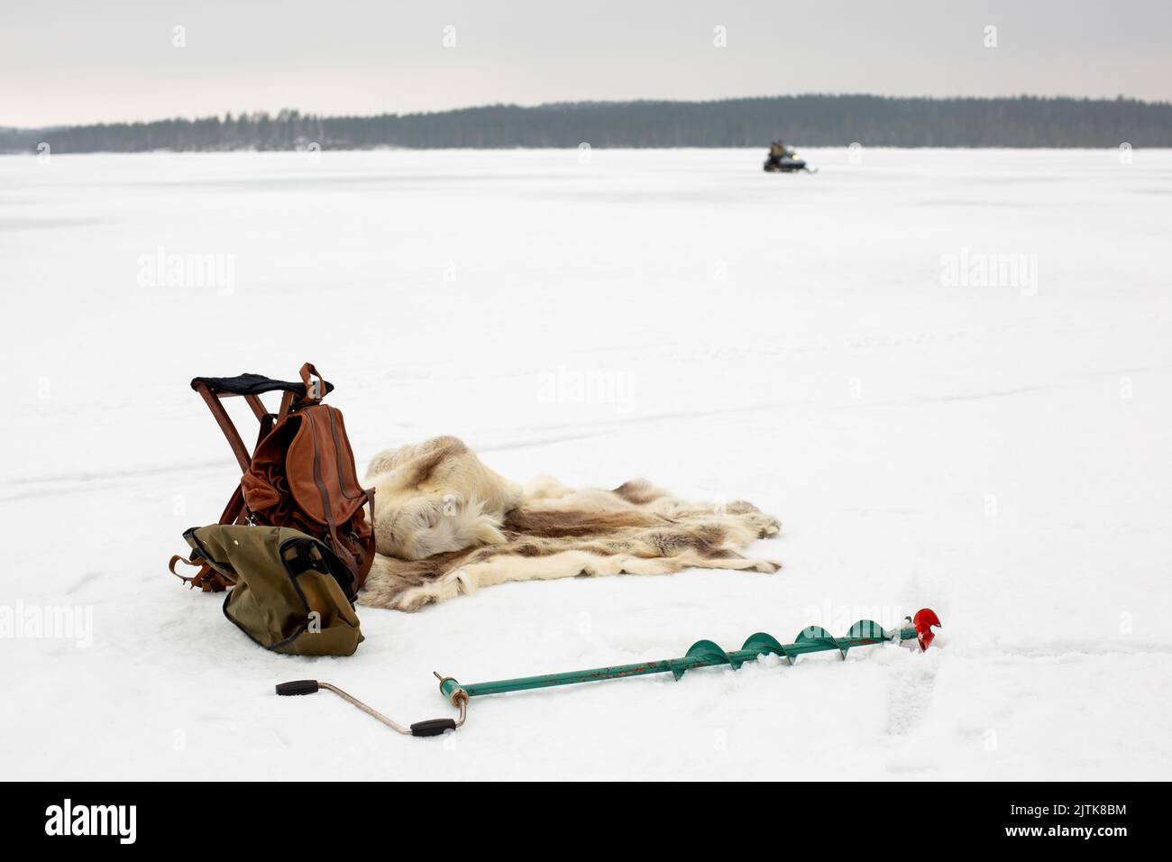 Backpack kept by animal skin and ice auger on snow in winter Stock ...