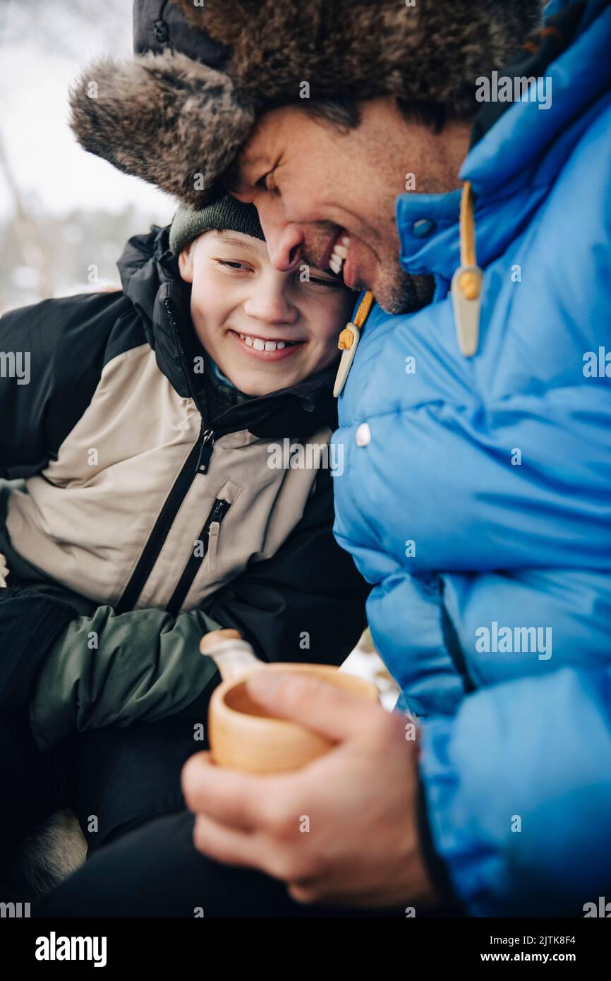 Happy father holding cup of tea embracing son in warm clothing Stock ...