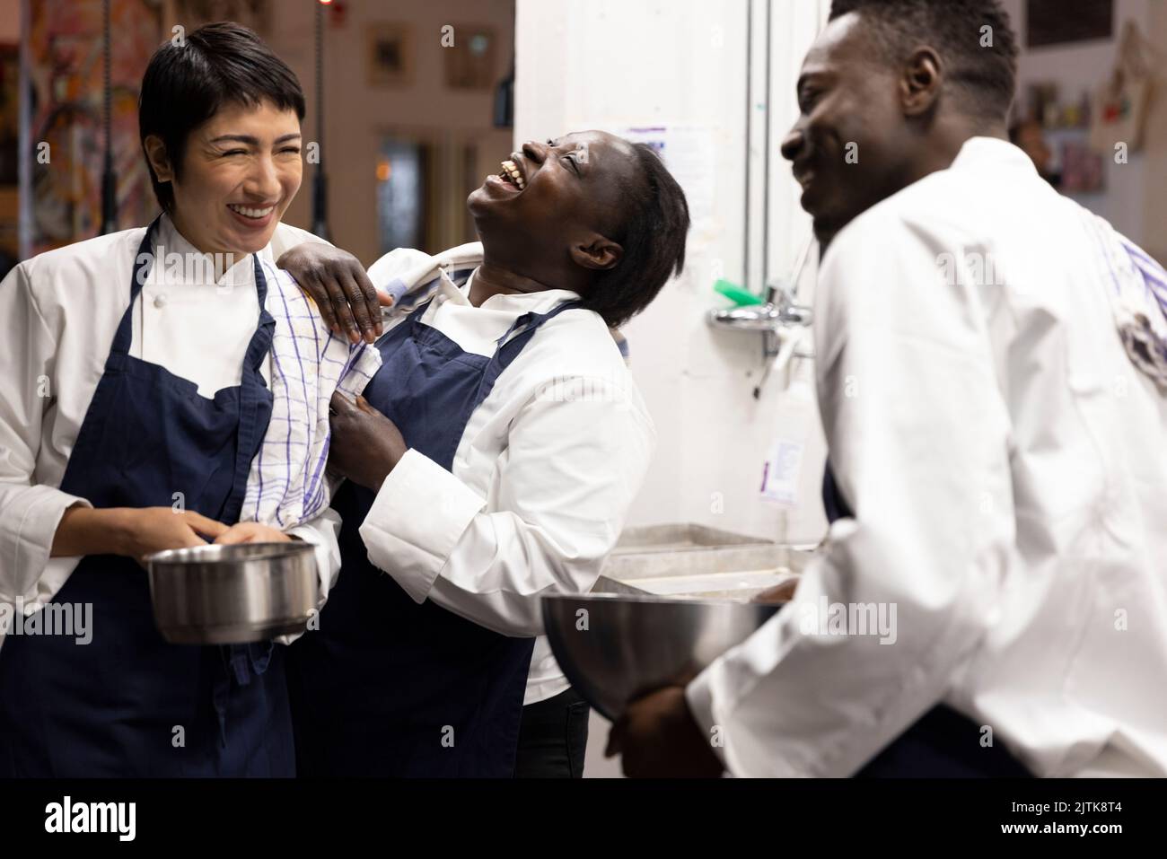 Multiracial chefs laughing while working in kitchen of restaurant Stock ...