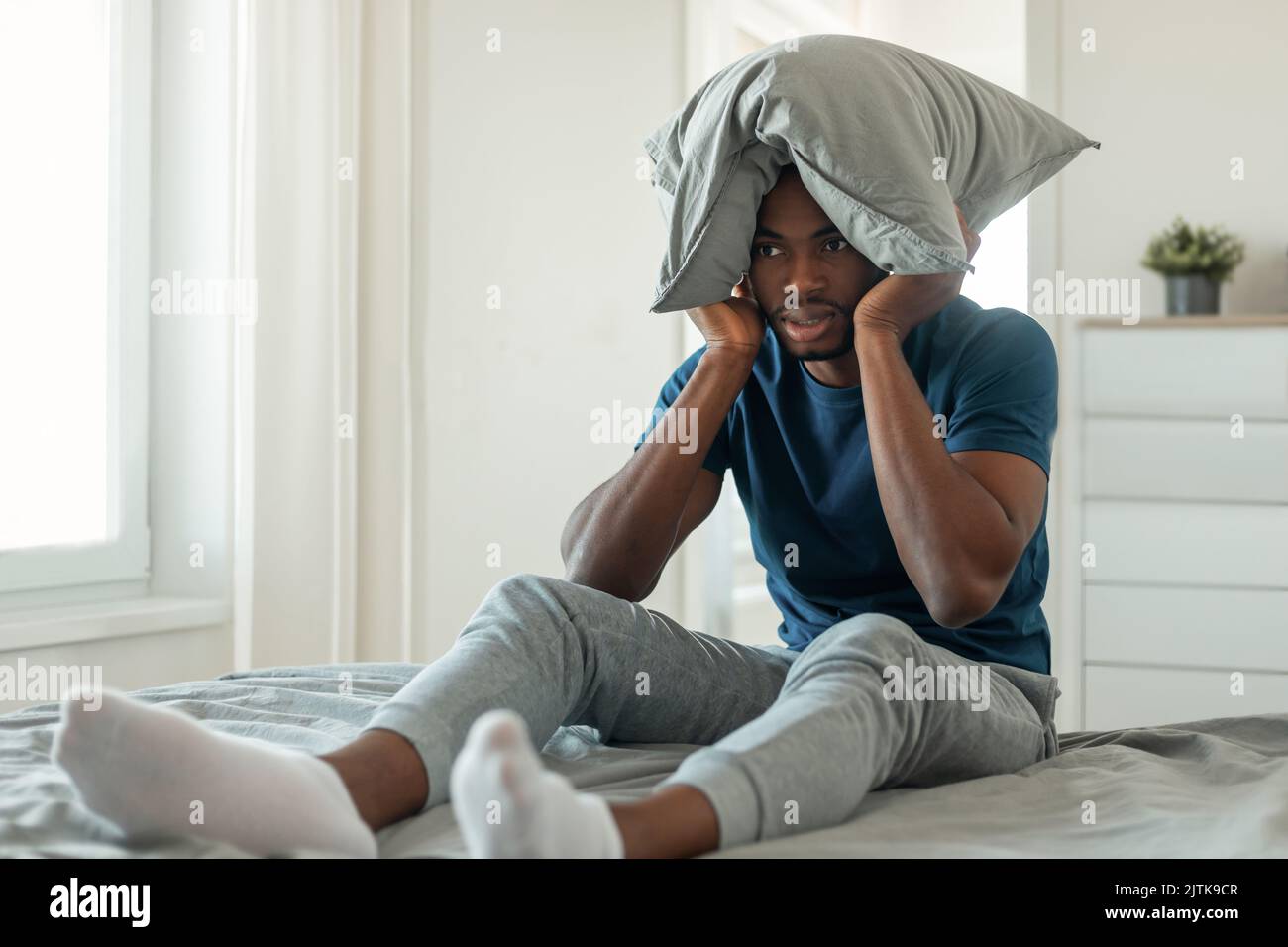 African Man Covering Head With Pillow Having Insomnia In Bedroom Stock ...