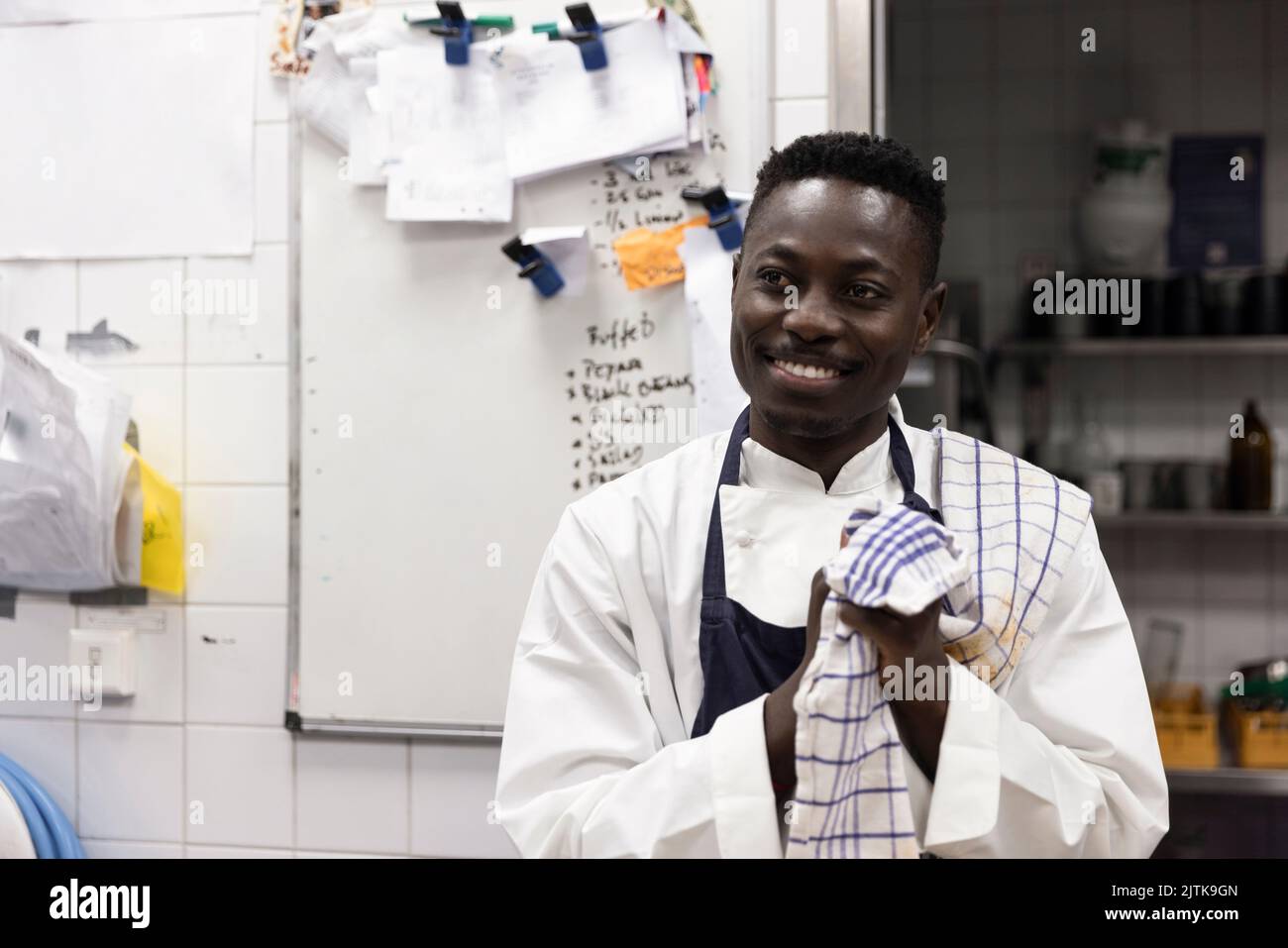 Smiling chef wiping hands while standing in commercial kitchen Stock ...