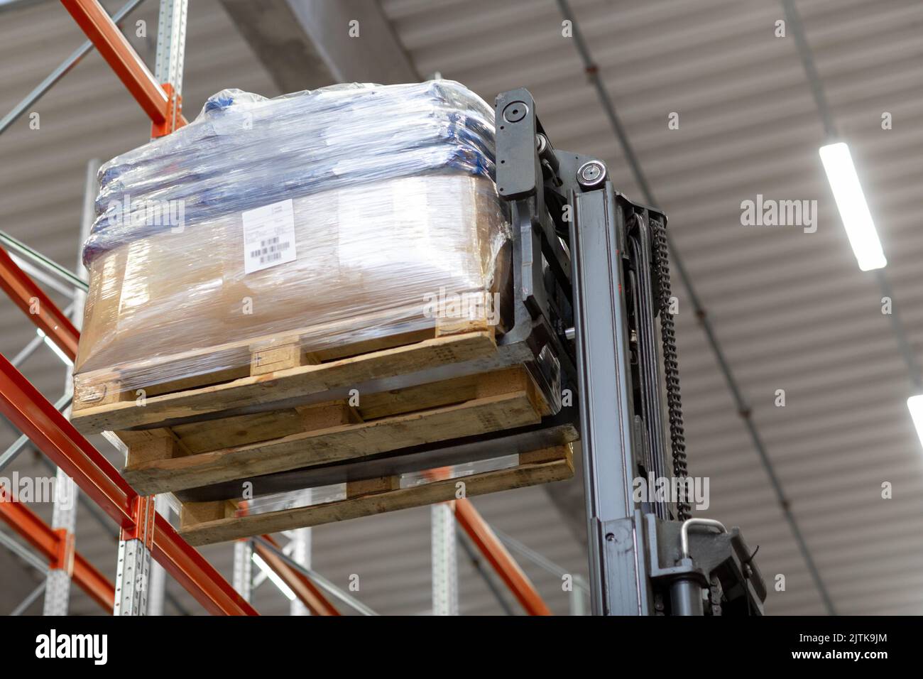 forklift loader loading cargo to warehouse shelves Stock Photo - Alamy