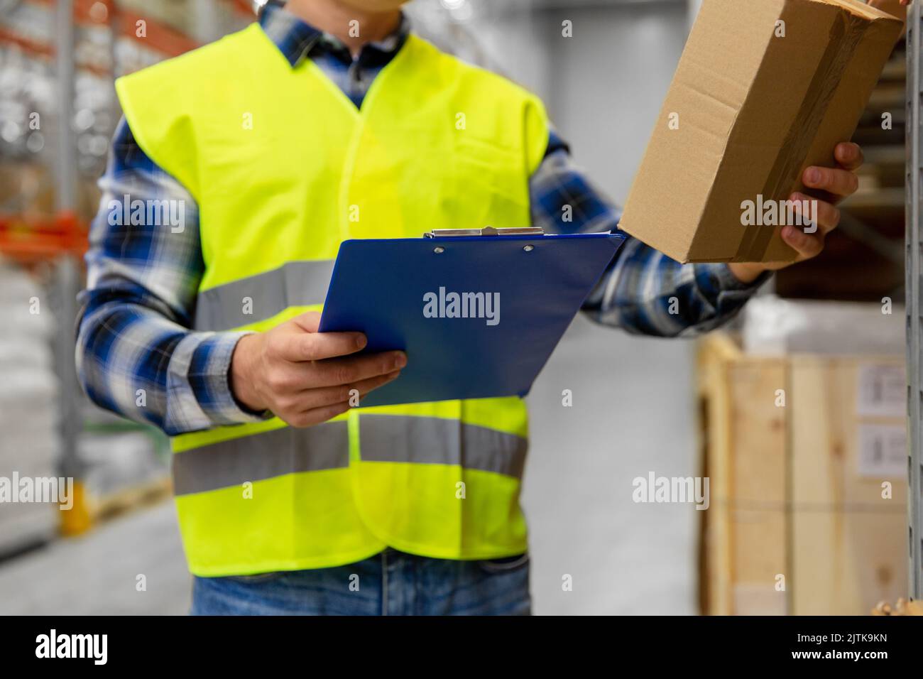 worker with box and clipboard at warehouse Stock Photo - Alamy