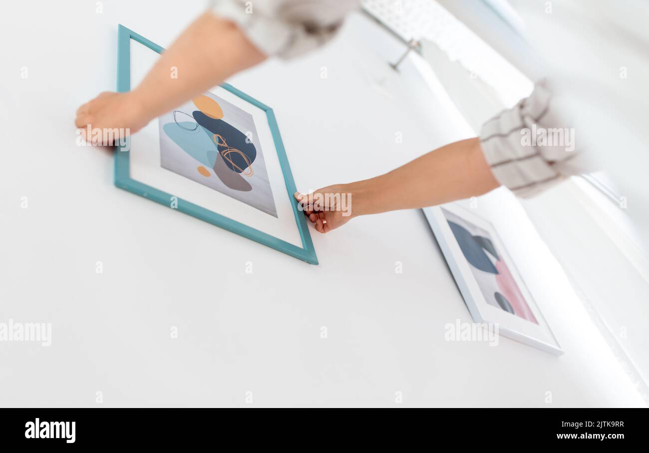 close up of hands hanging picture in frame on wall Stock Photo - Alamy