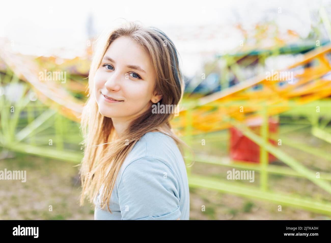 Happy young Gen Z woman with trendy blue hair in an amusement park ...