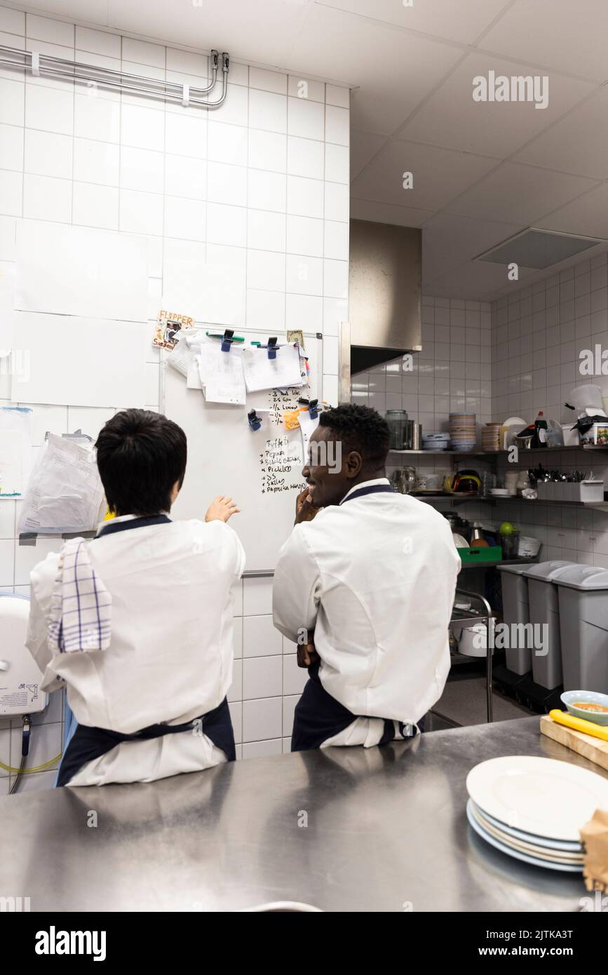 Male and female colleagues planning over whiteboard at restaurant ...