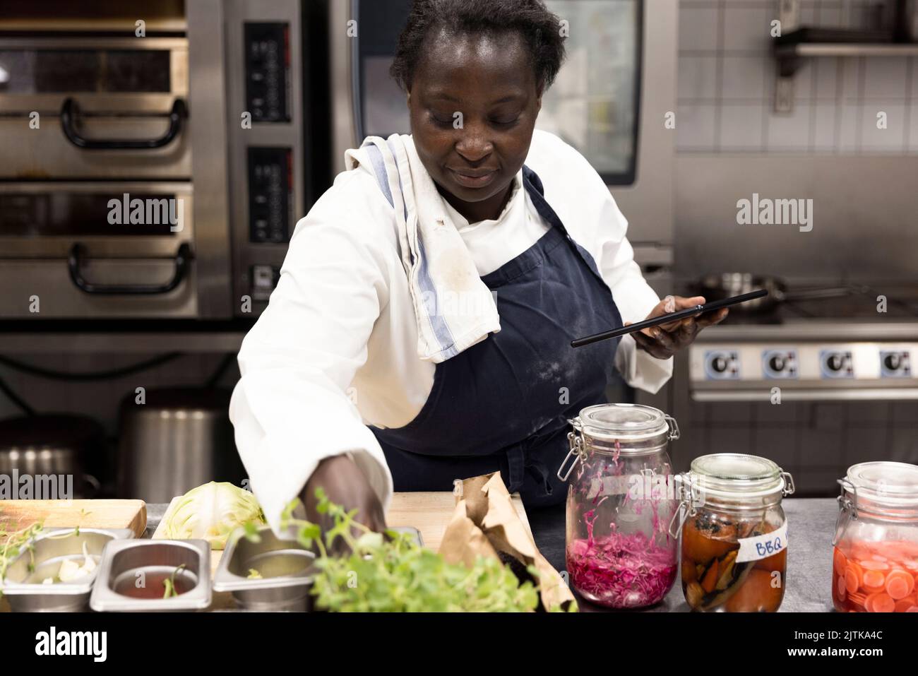 Chef holding digital tablet while preparing food in kitchen of ...