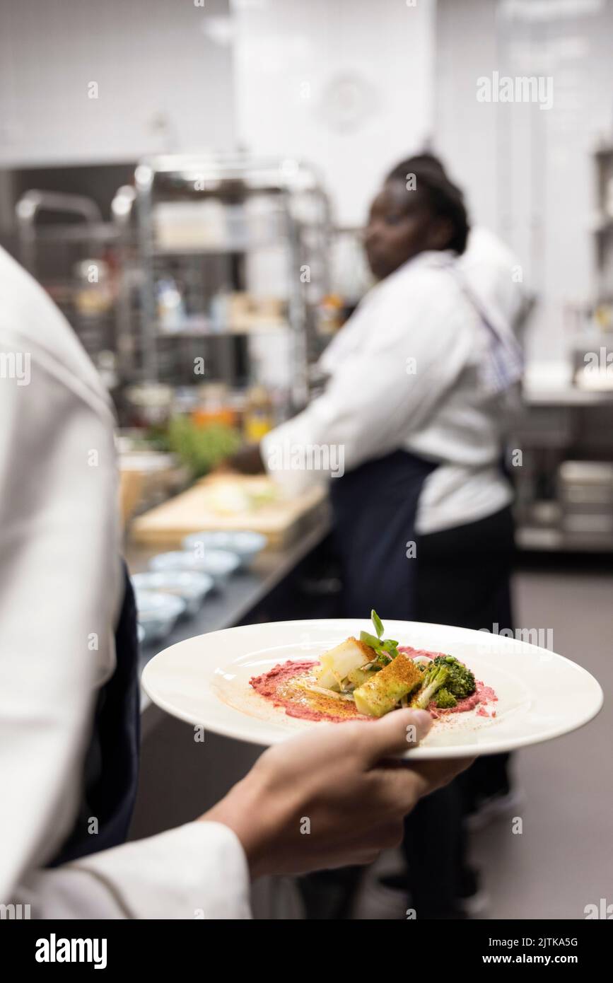 Rear view of chef carrying food in plate at restaurant kitchen Stock ...