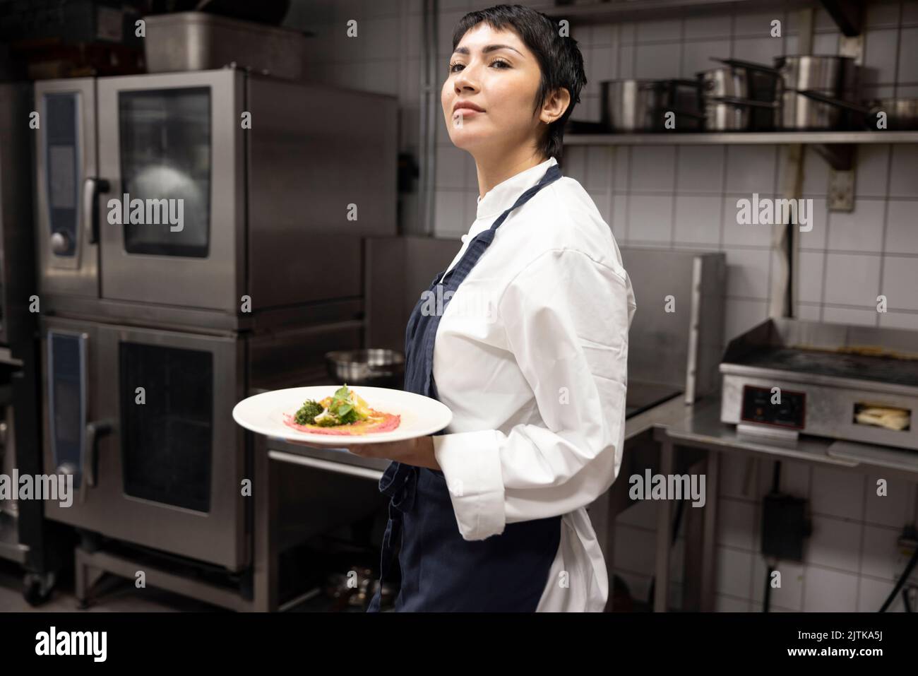 Chef walking with food in plate at commercial kitchen Stock Photo - Alamy