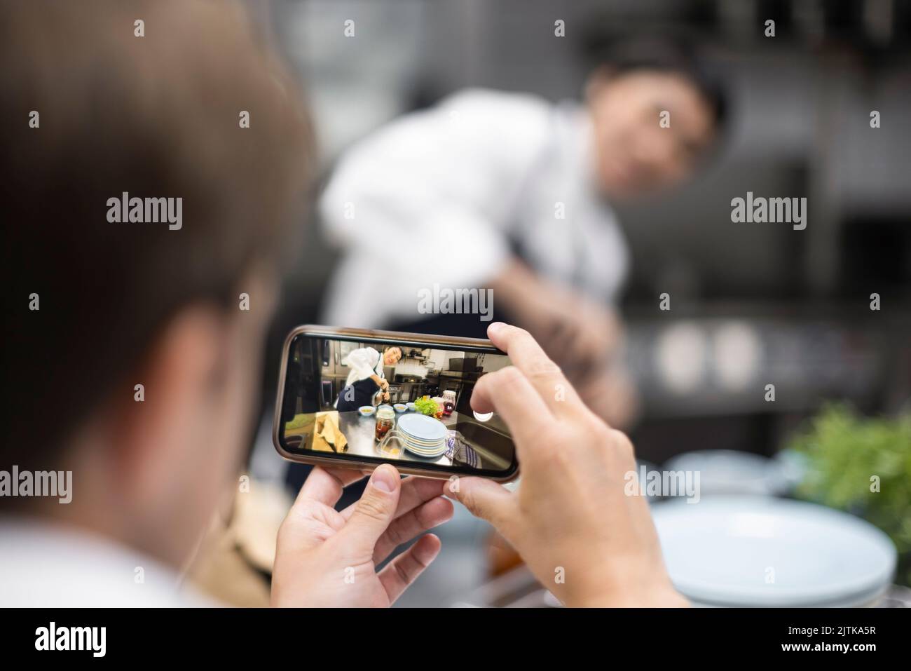 Chef photographing colleague preparing food in restaurant Stock Photo ...