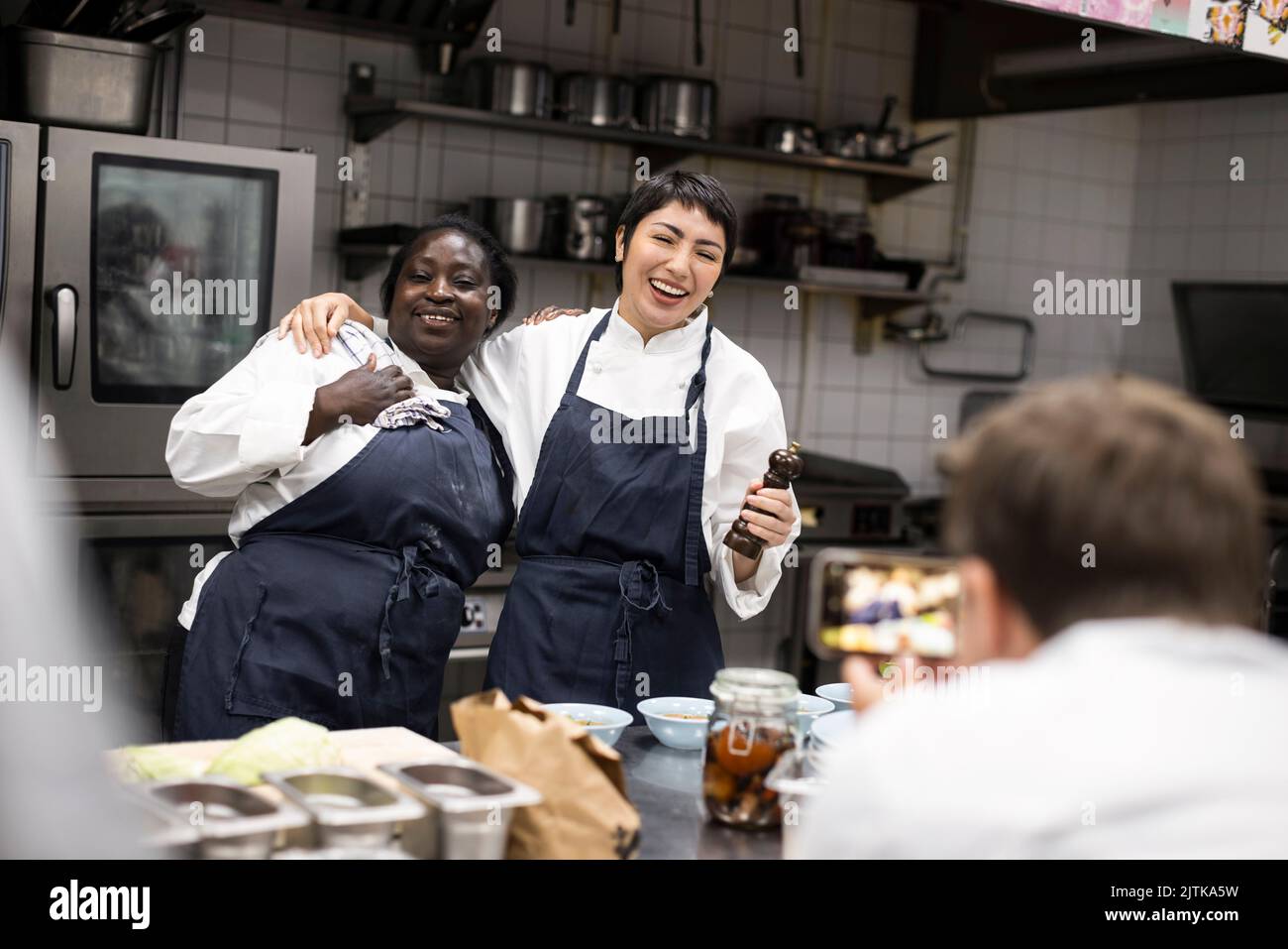 Male chef photographing happy colleagues at commercial kitchen Stock ...