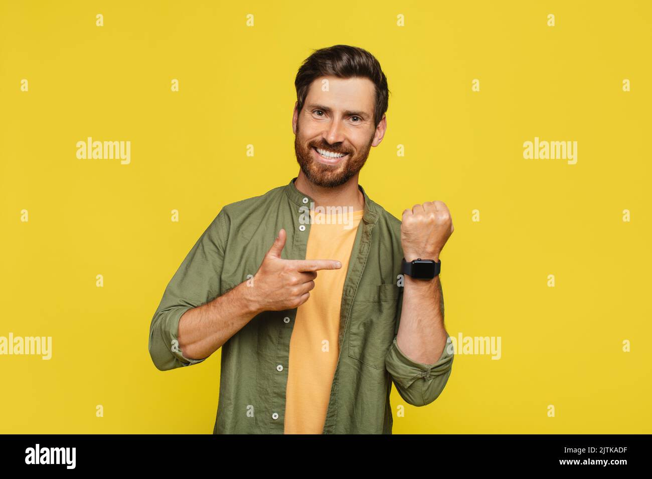 Handsome middle aged man wearing smart watch and pointing at it ...