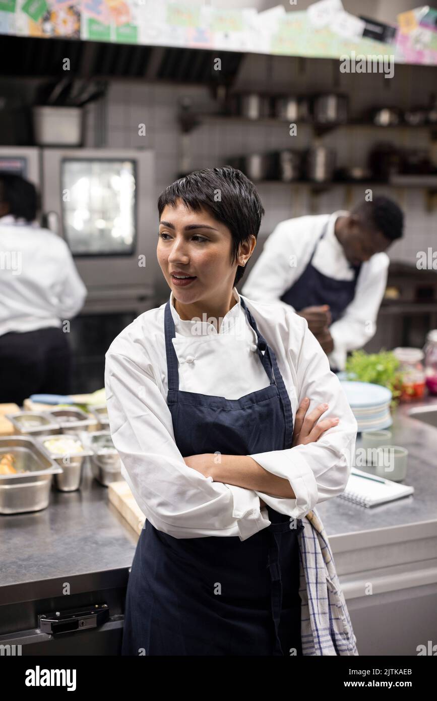 Chef with arms crossed standing in front of kitchen counter at ...