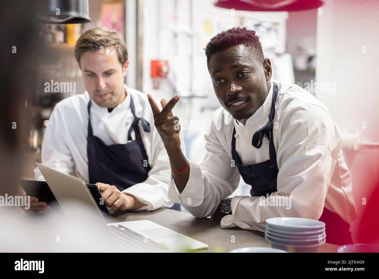 Male chefs discussing at kitchen counter in restaurant Stock Photo - Alamy