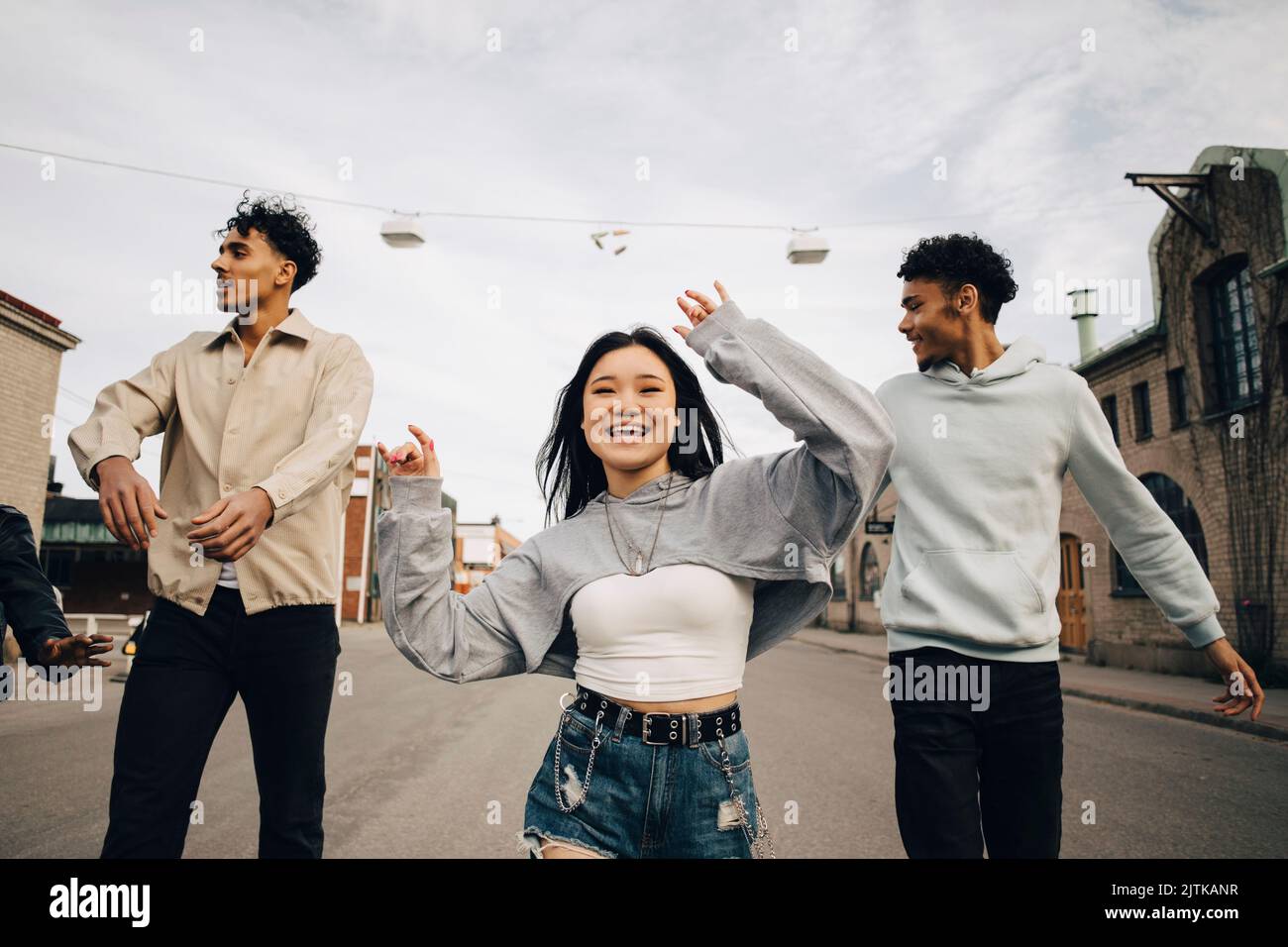 Happy multiracial young woman dancing with friends on street in city ...