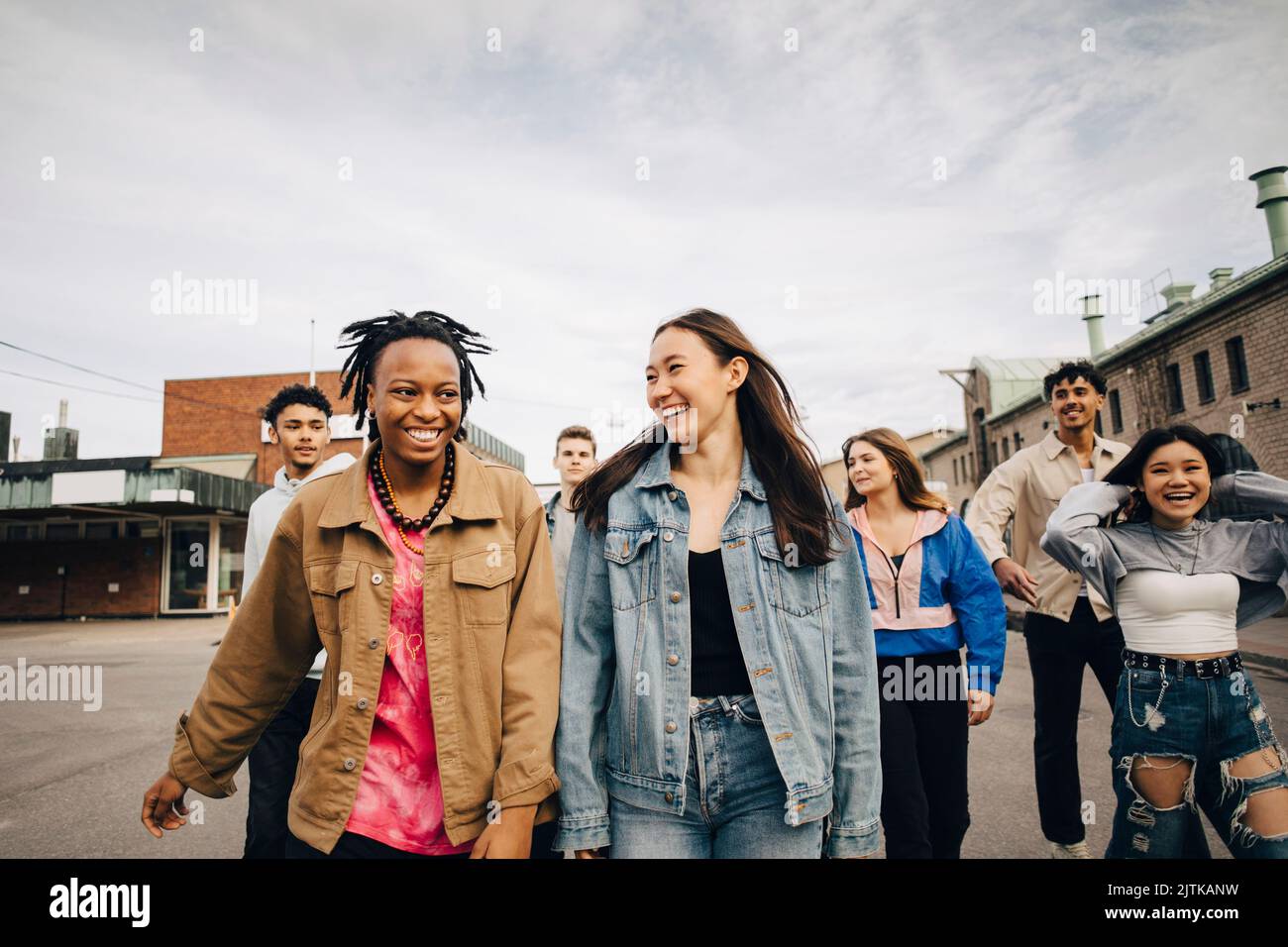 Happy multiracial young friends walking on city street Stock Photo - Alamy